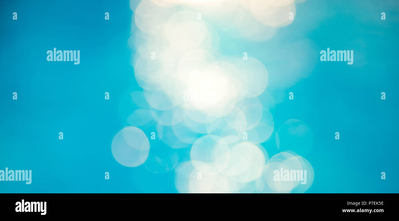 Soft focus bokeh light effects over a rippled, blue water background in ...