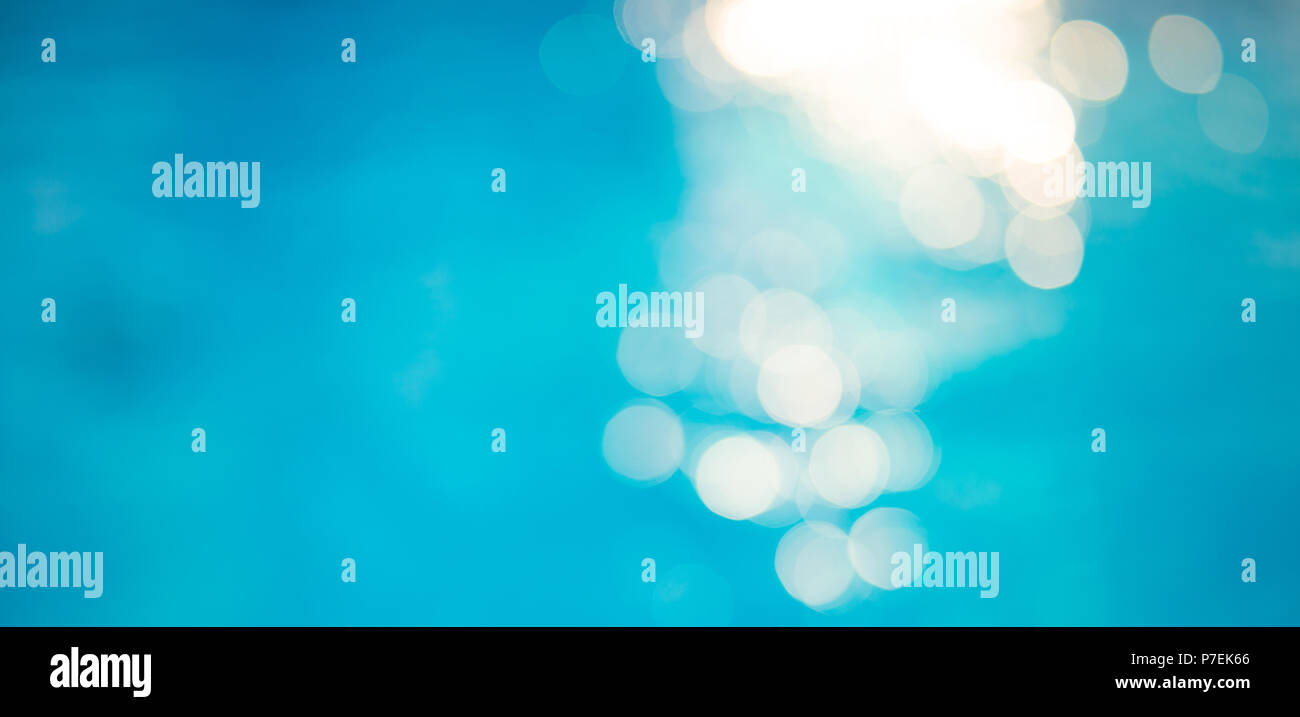 Soft focus bokeh light effects over a rippled, blue water background in ...