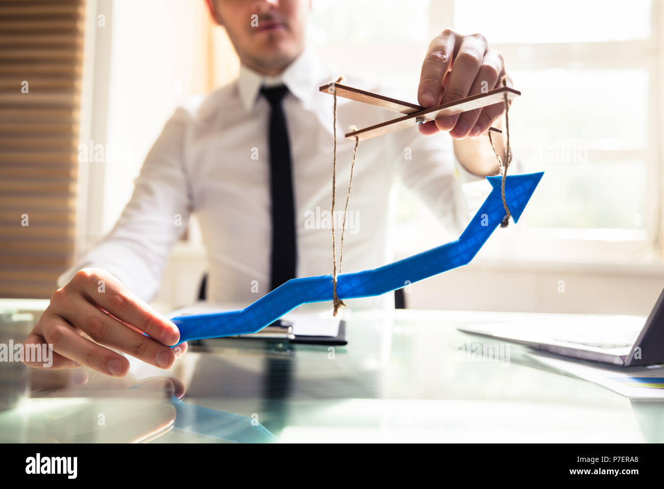Businessperson's Hand Manipulating Blue Arrow With Rope Stock Photo - Alamy
