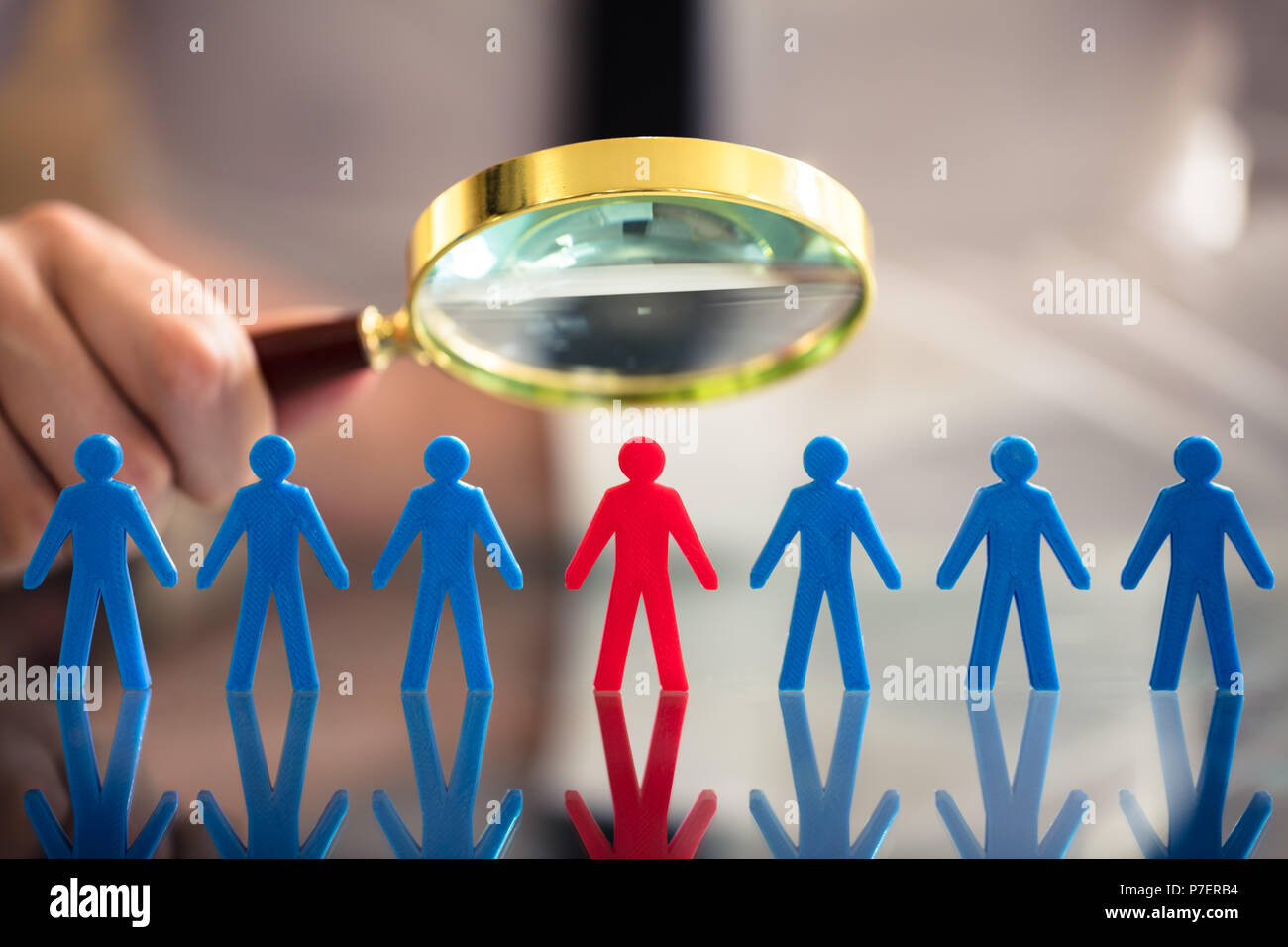 Businessperson's Hand Holding Magnifying Glass Over Red Human Figure ...