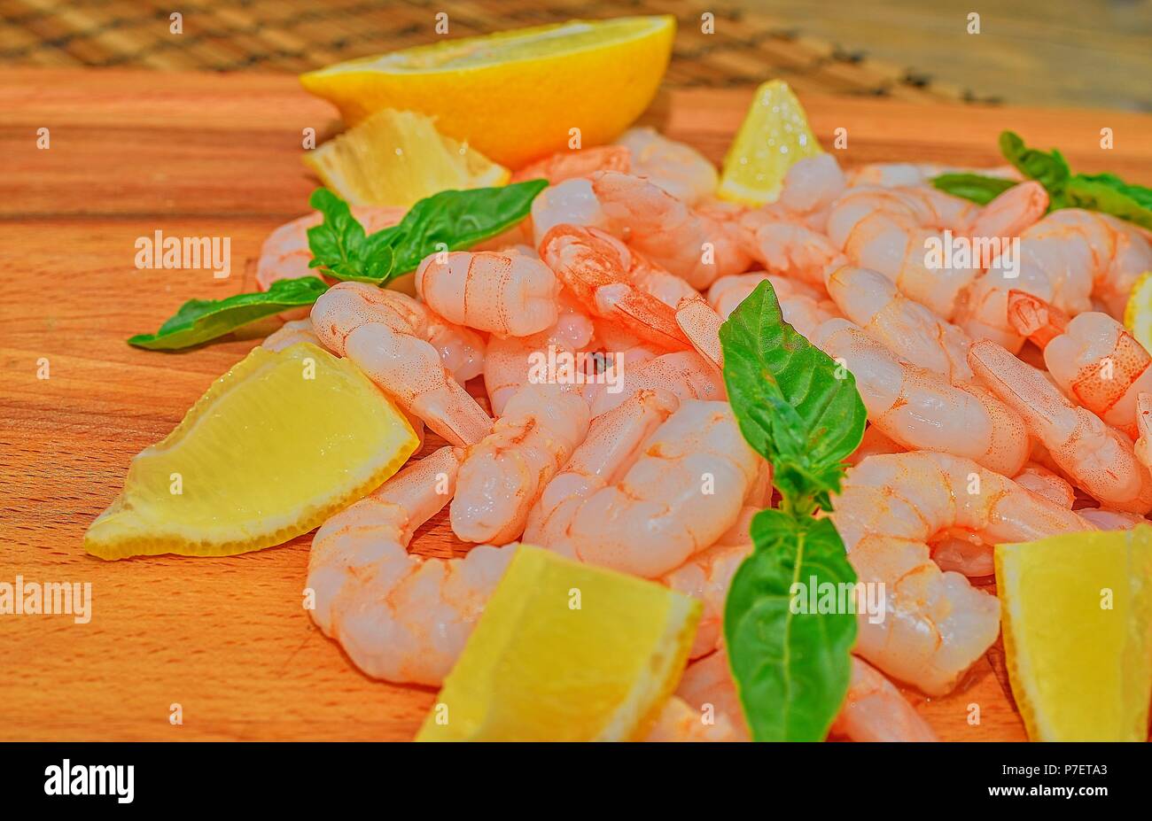 Cooked and peeled prawns with slices of lemon and leaves of basil on ...