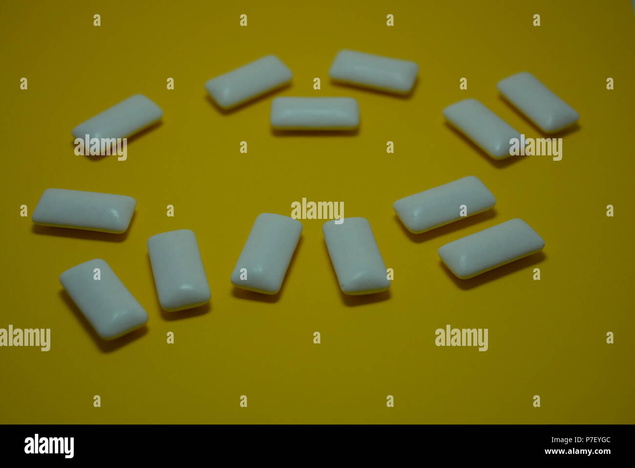 On bright yellow paper are located white pillows from chewing gum Stock ...