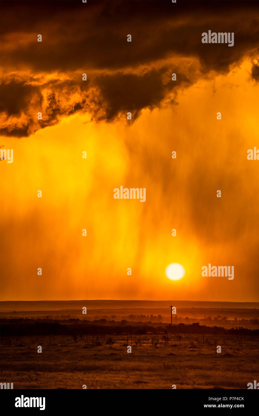 Pouring rain during a lightning storm framed by a low, orange sunset ...