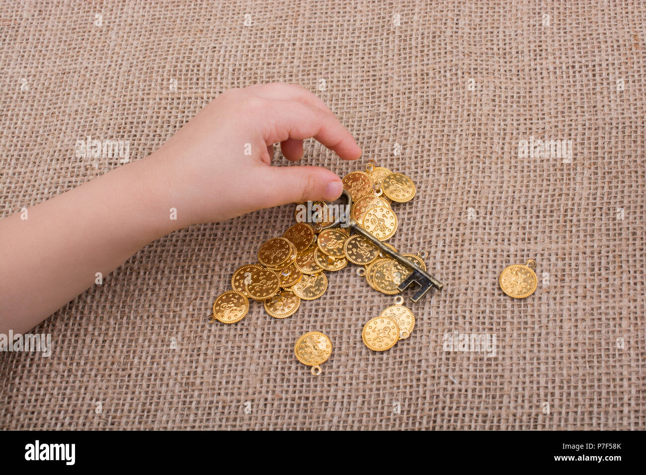 Hand holding a retro styled key over fake gold coins Stock Photo - Alamy