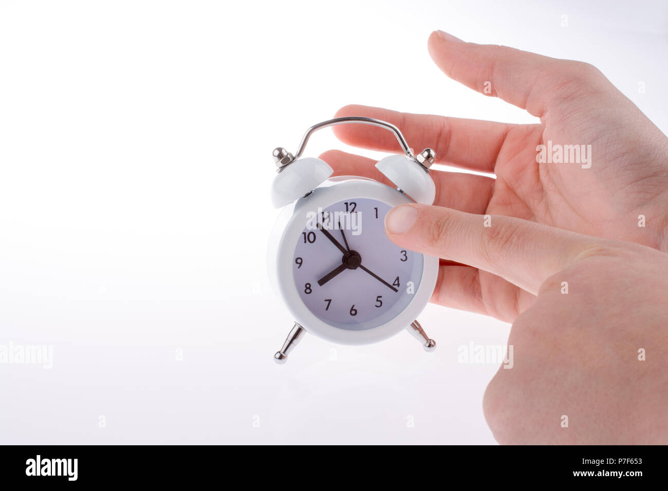 Alarm clock in hand on a white background Stock Photo - Alamy