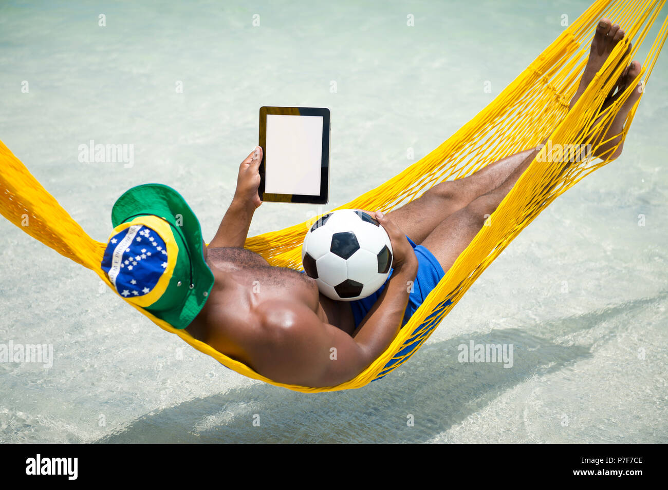 Brazilian footballer wearing flag hat and using tablet computer with a ...