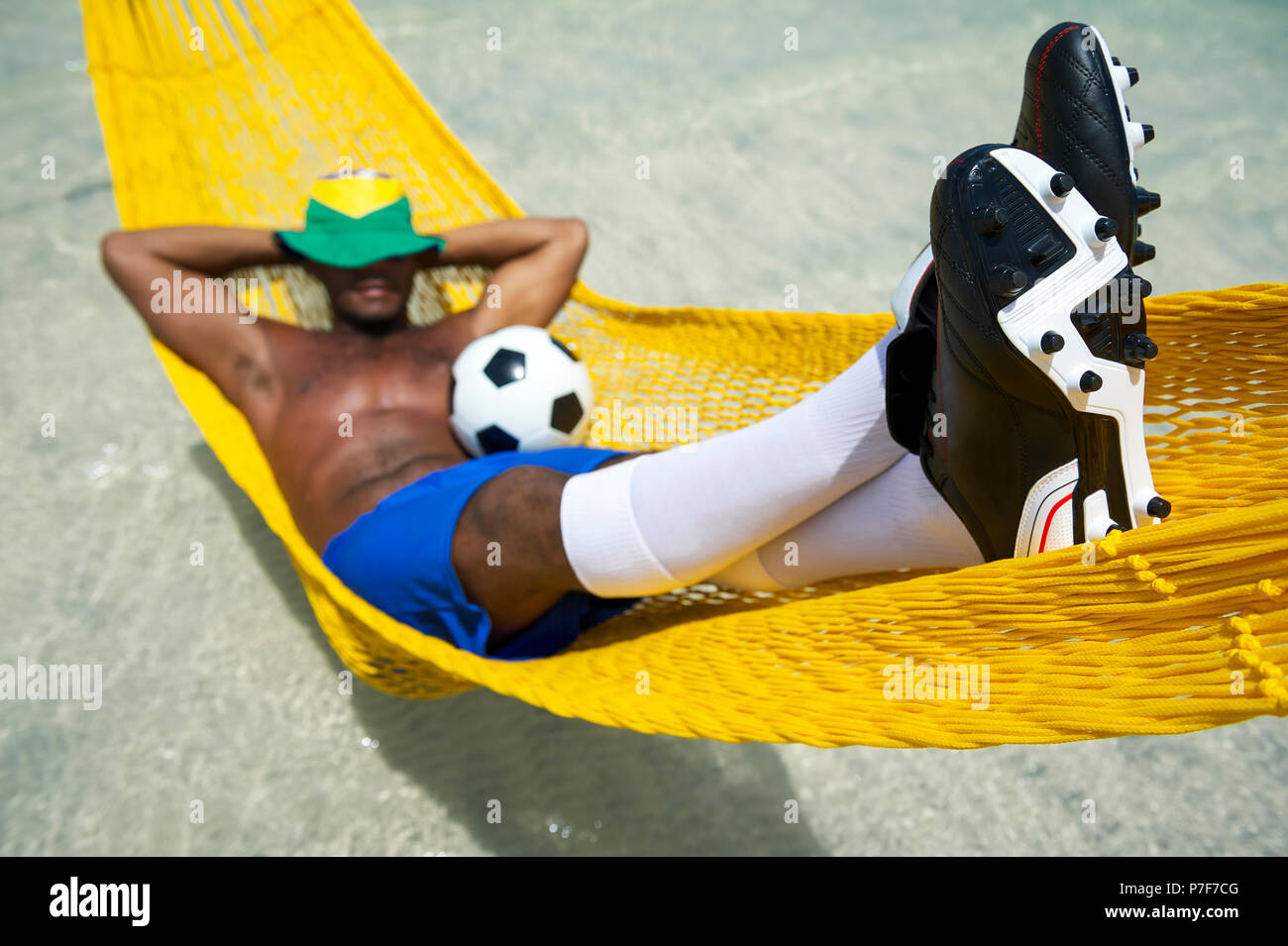 Brazilian soccer player in his boots relaxing in a beach hammock with a ...