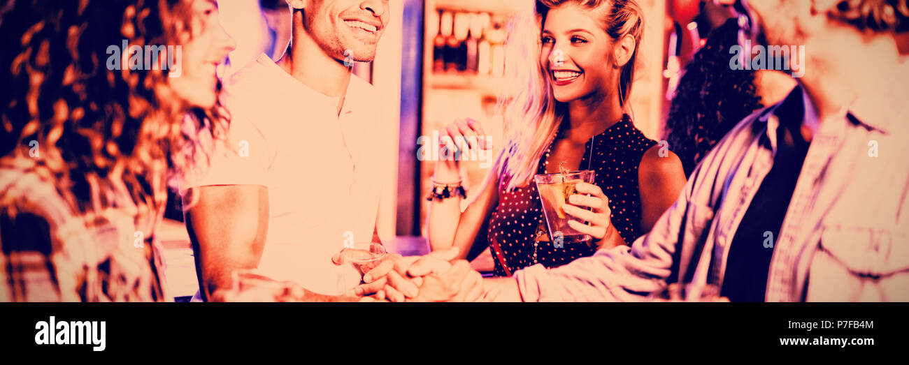 Friends doing handshake by counter in club Stock Photo - Alamy