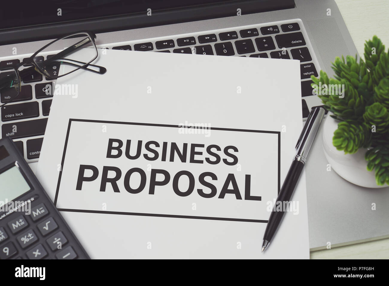 Business Proposal on white paper placed on top of laptop computer ...