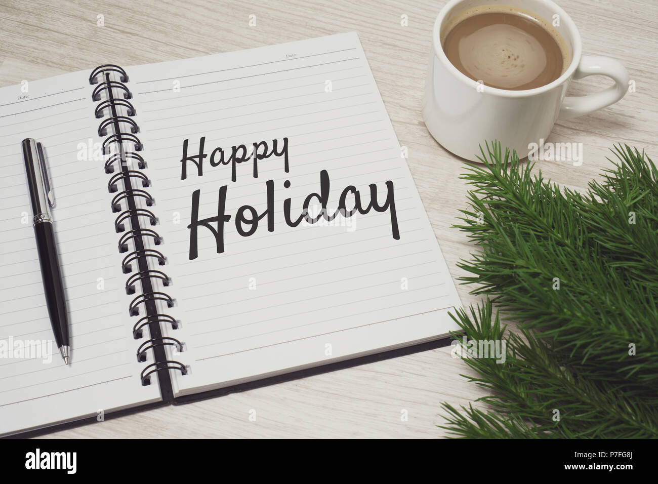 Happy Holiday written on notebook placed on top of wood desk. Festival ...