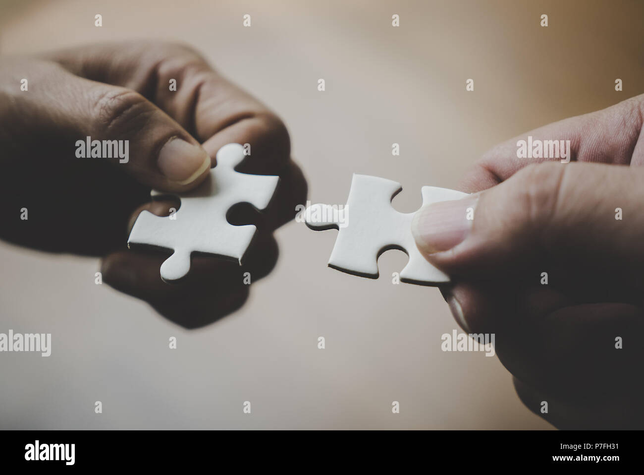 Two hands joining together two jigsaw puzzles Stock Photo - Alamy