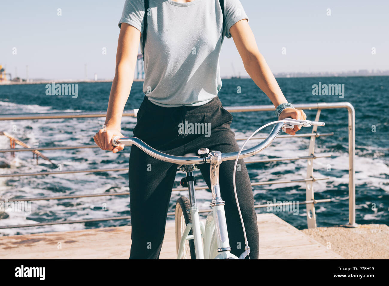 Close-up female holding handlebars of cruiser bike. Young woman wearing ...