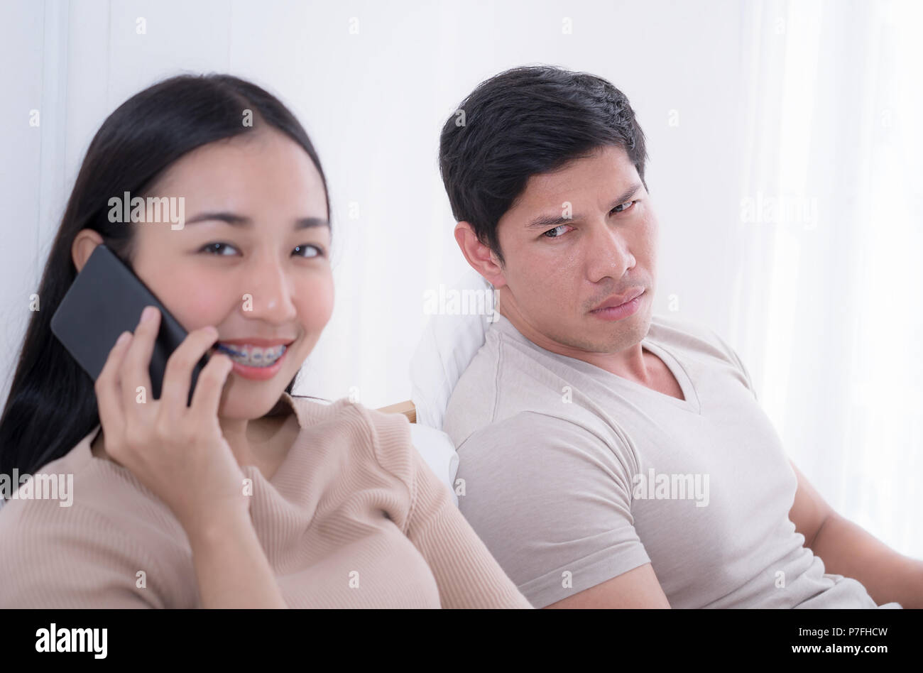 Angry Husband on bed when wife is ignoring but only take on phone Stock ...