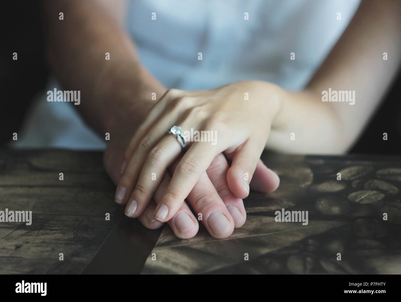 Woman's hand with an engagement ring on man's hand, date in the cafe ...