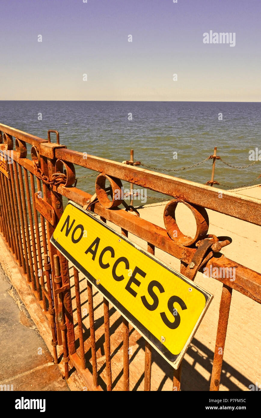 Rusty metal gates with no access to sea sign Stock Photo - Alamy