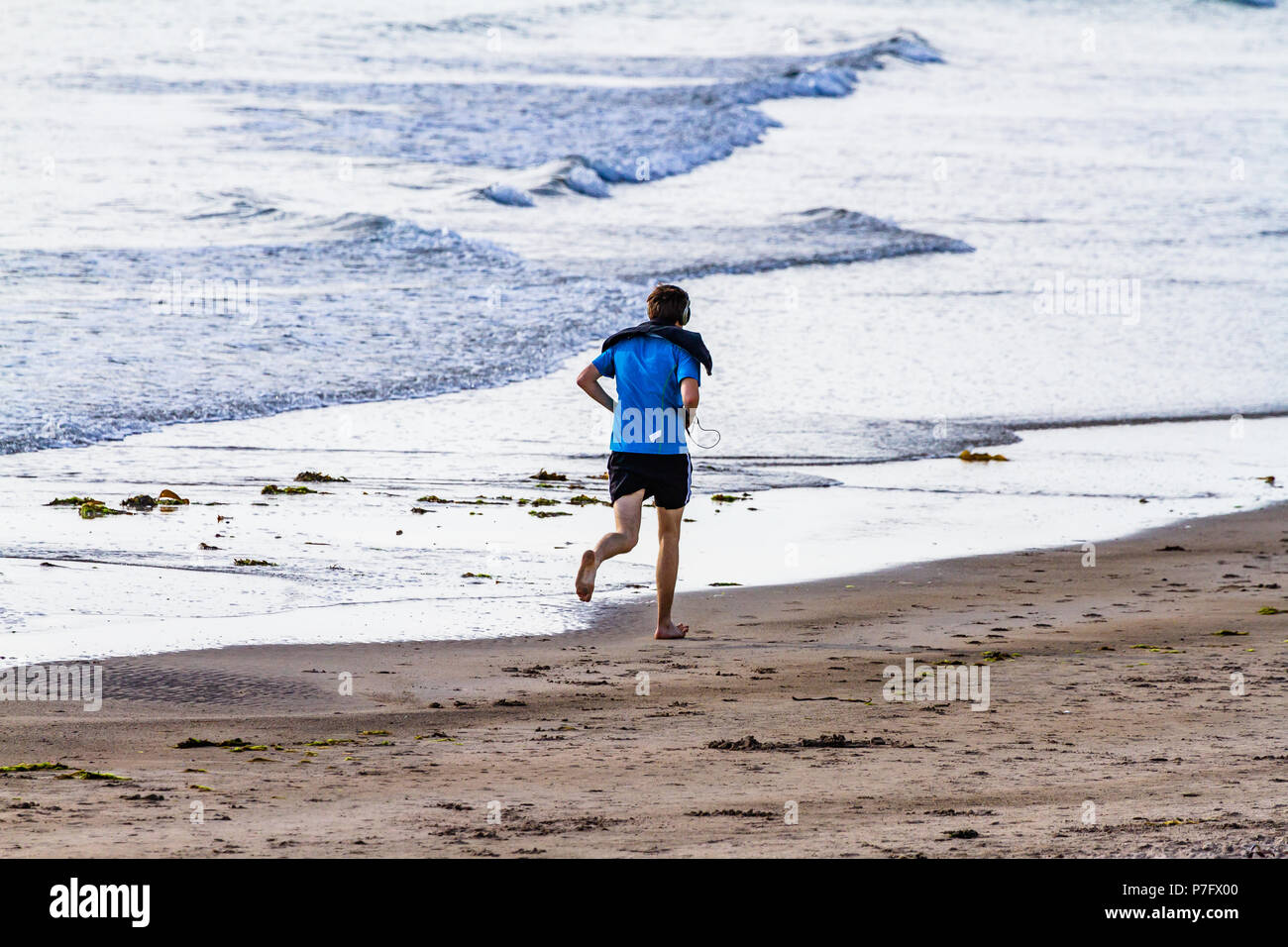 Jogger running by the sea along a beach, UK Stock Photo - Alamy
