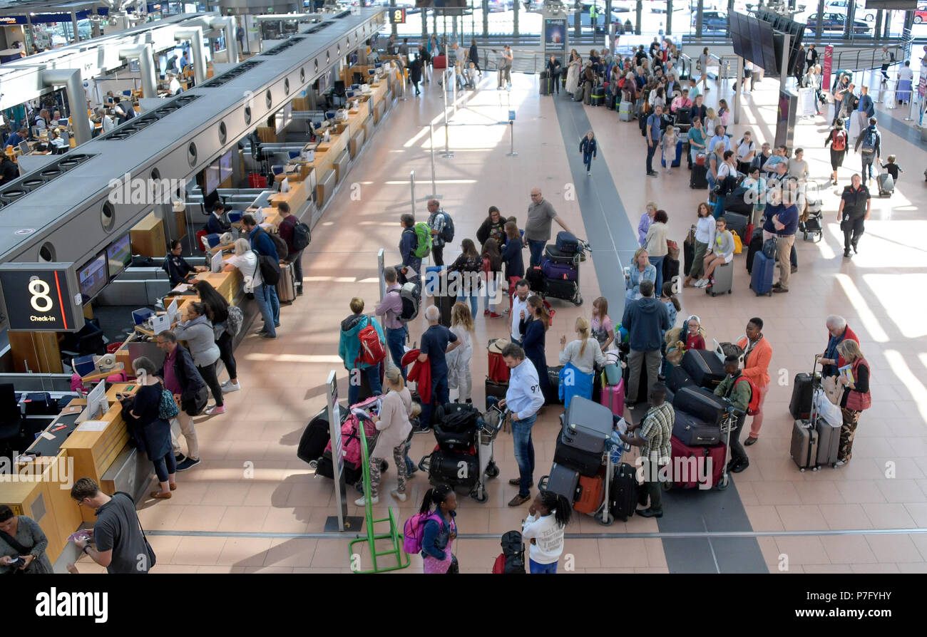 06 July 2018, Germany, Hamburg: Airline passengers waiting in long queues by the check-in ...
