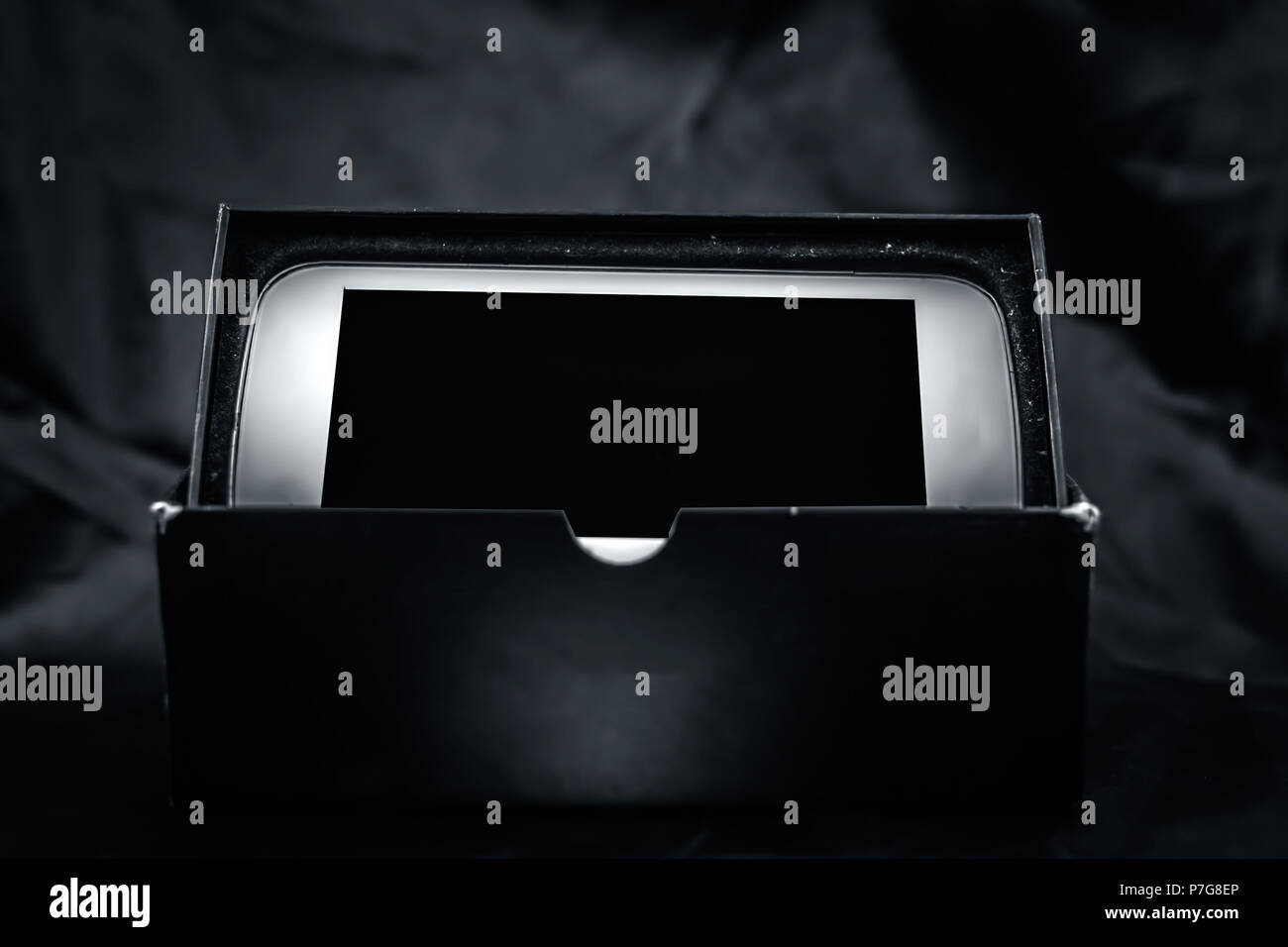Close up of an Un -boxed digital smart phone in its box on a dark shiny ...
