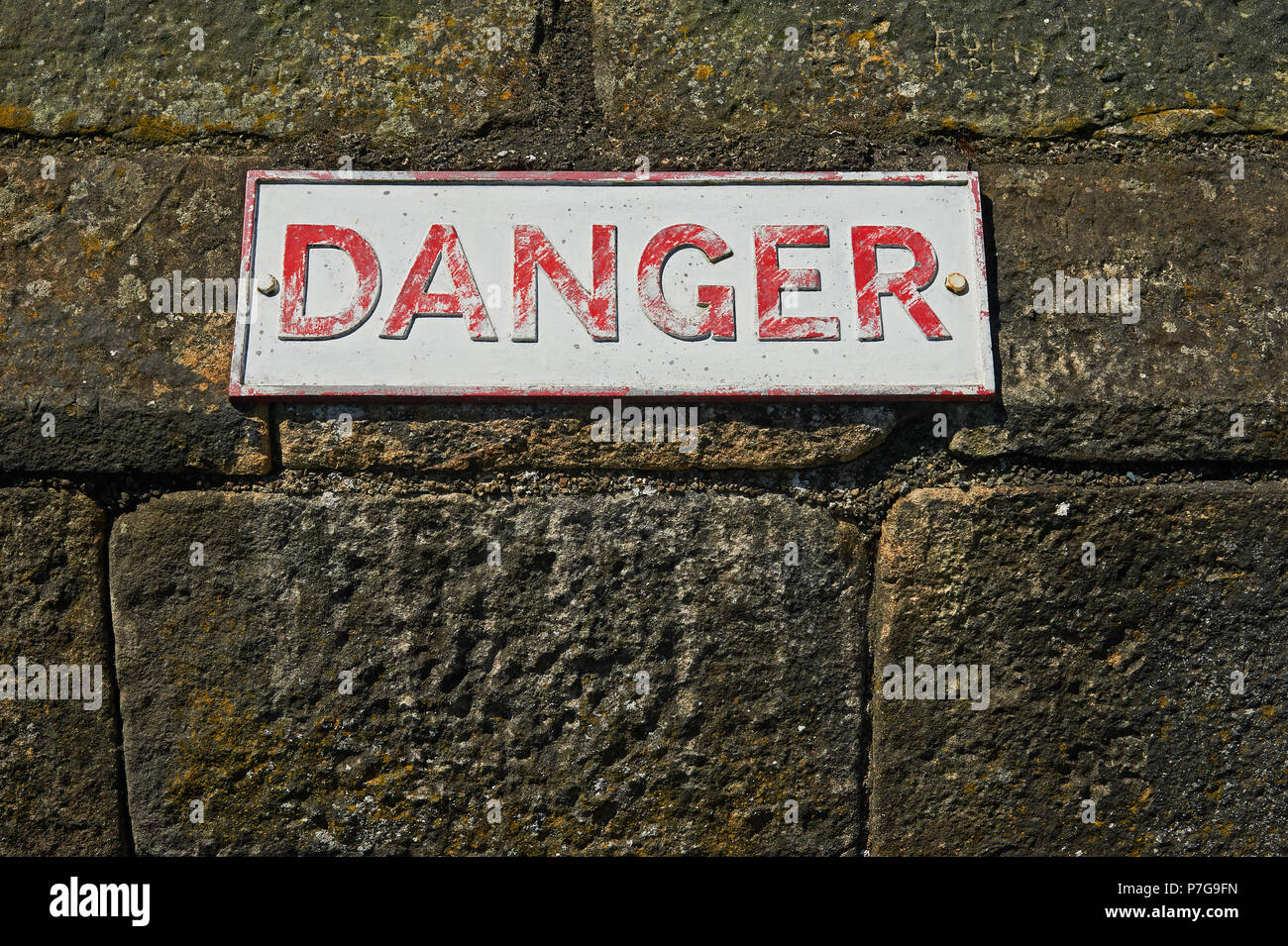 Metal plaque with the word DANGER on a stone wall Stock Photo - Alamy