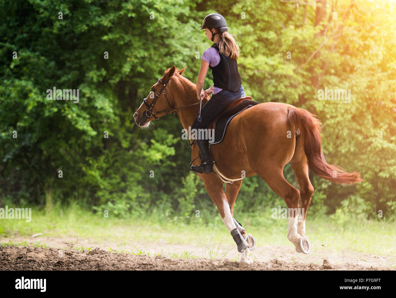 Young pretty girl - riding a horse with backlit leaves behind in spring ...