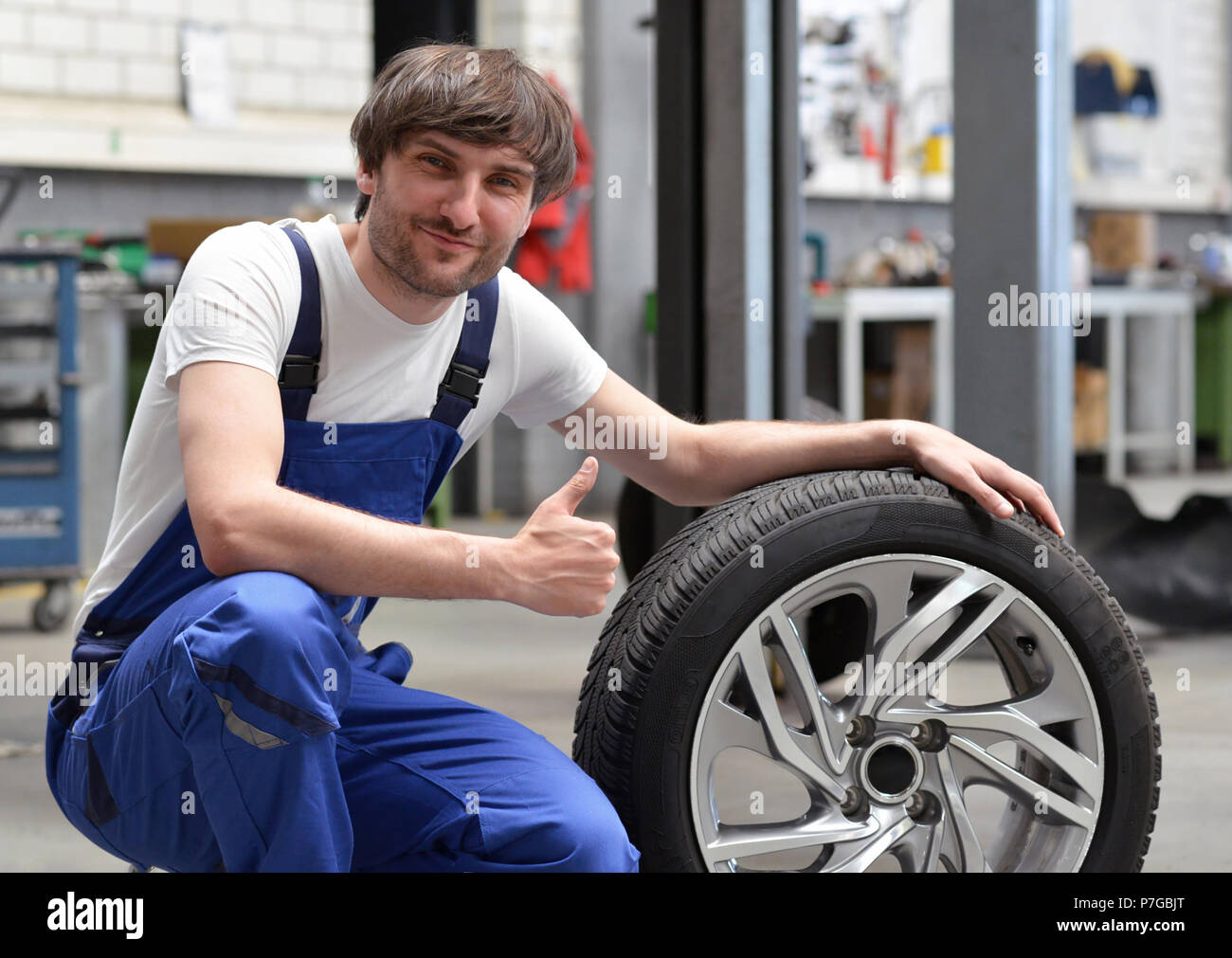 tire change in a car workshop by mechanic - portrait og smiling workmen ...