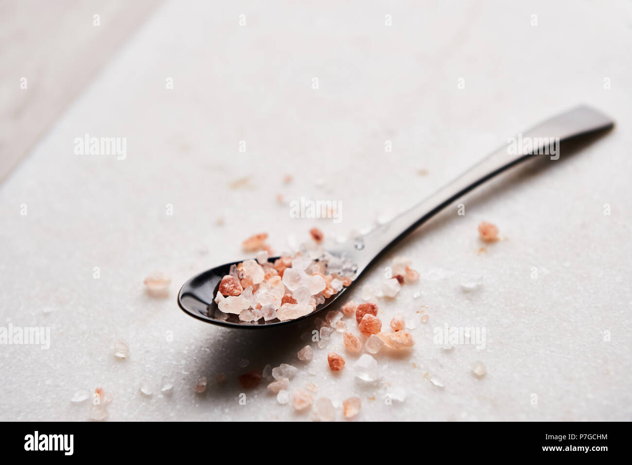 Black spoon of pink himalayan salt on marble table with copy space ...