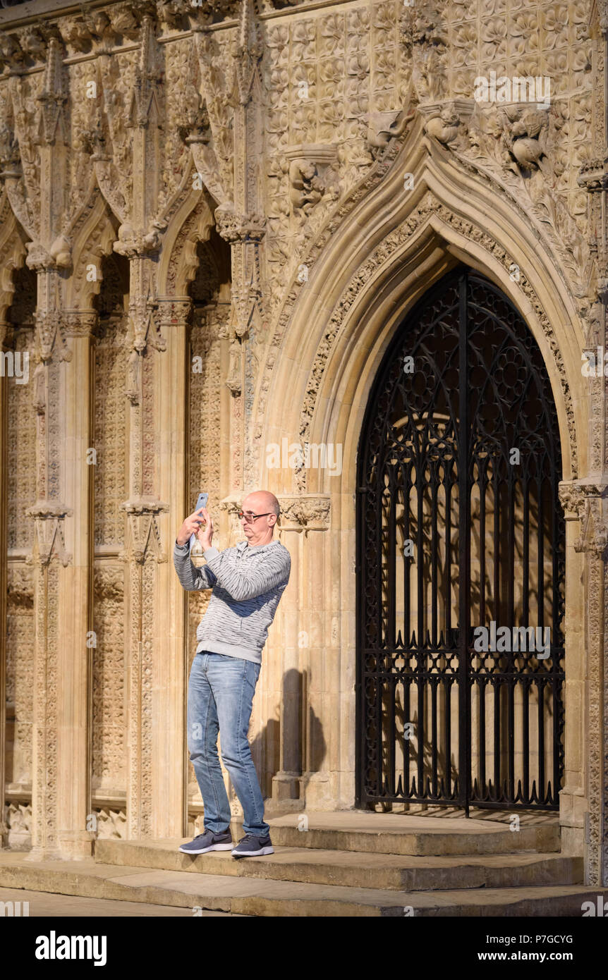 Visitor takes a photo in front of the stone rood screen at the medieval ...