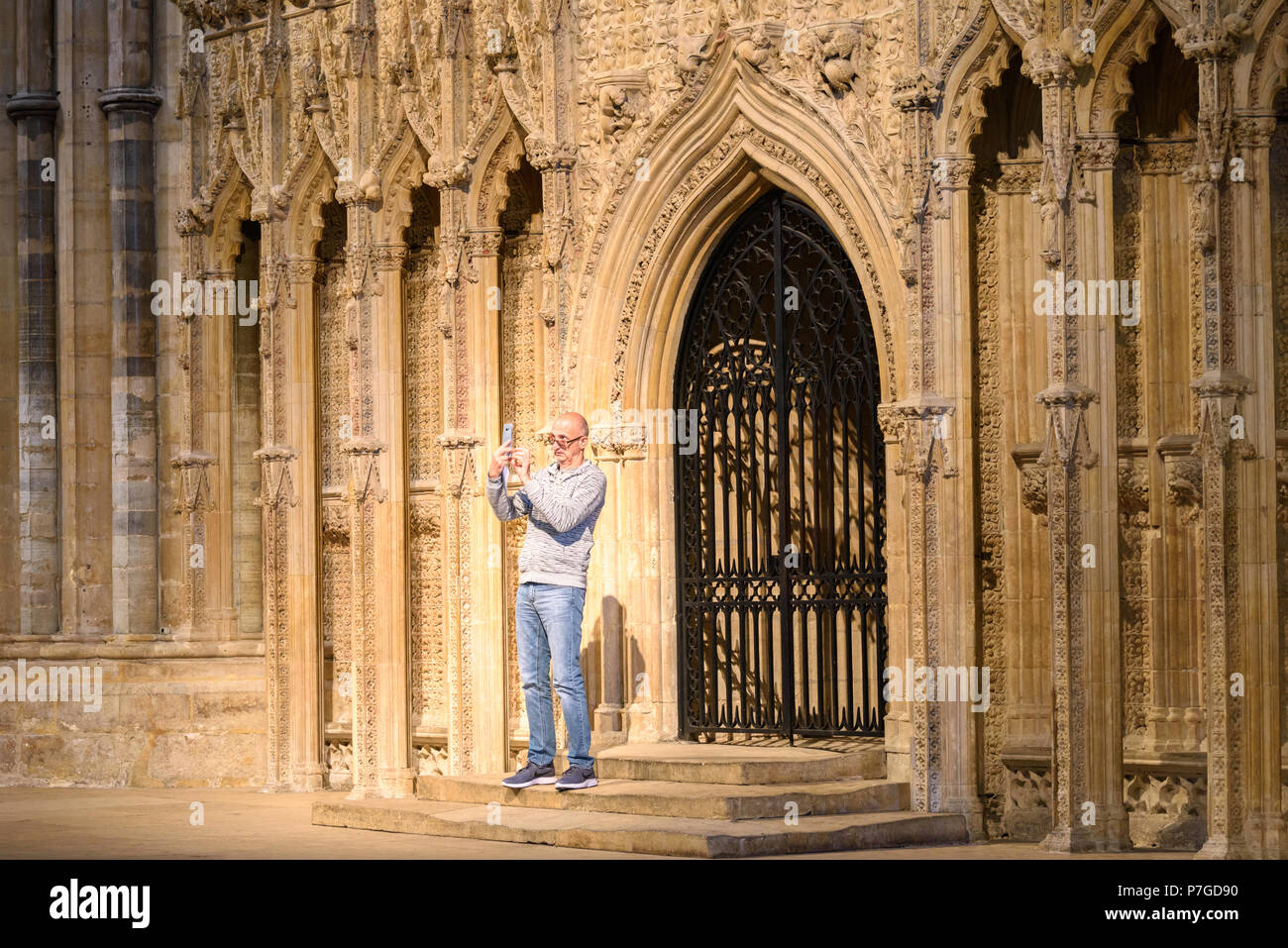 Visitor takes a photo in front of the stone rood screen at the medieval ...