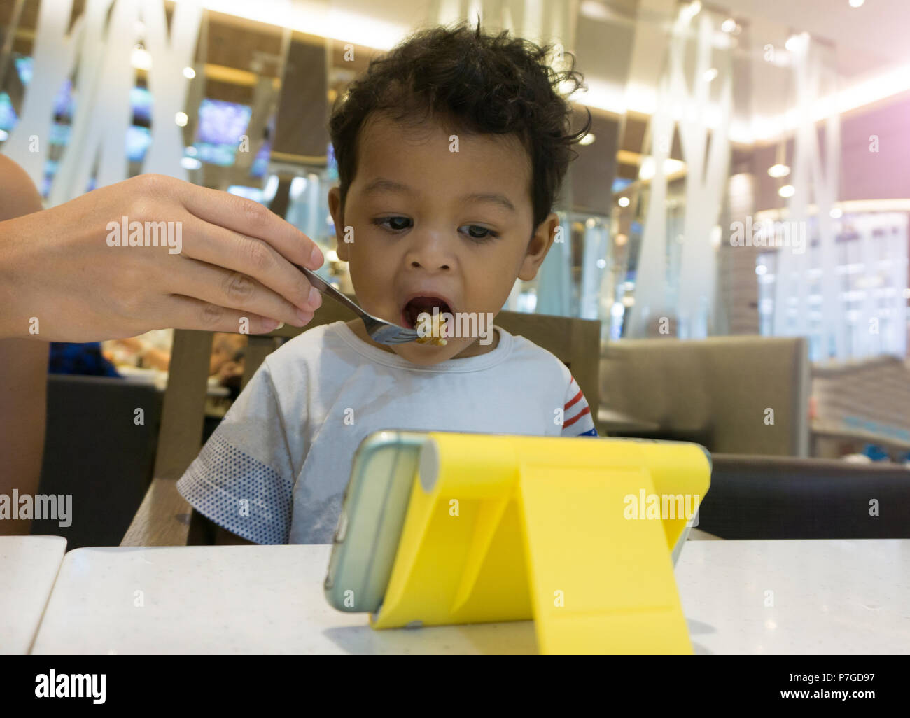 Asian kid watch smartphone her mother when eating the lunch Stock Photo ...