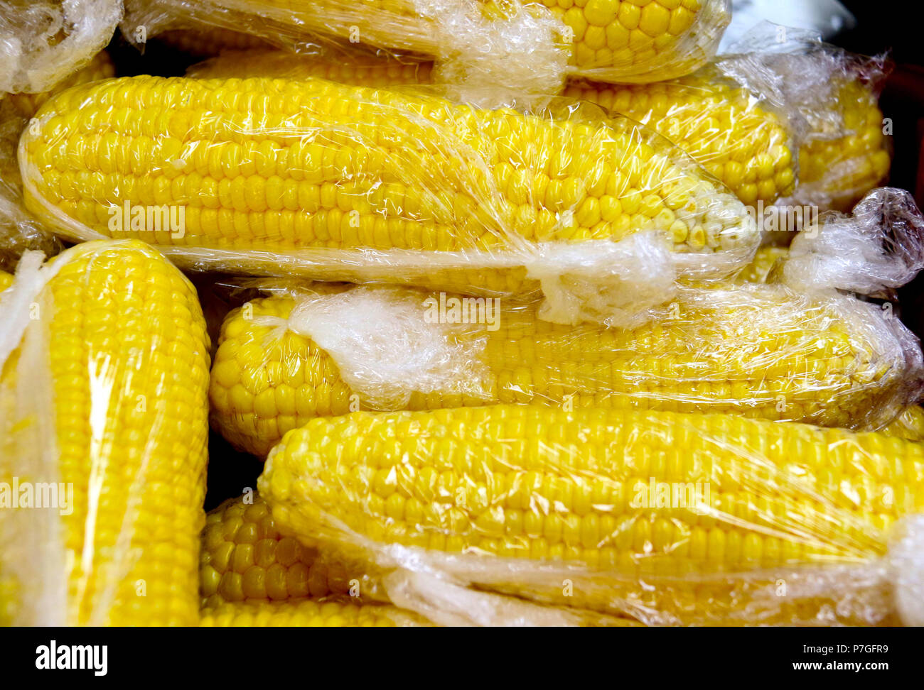 Raw sweet corn wrapped in cellophane Stock Photo - Alamy
