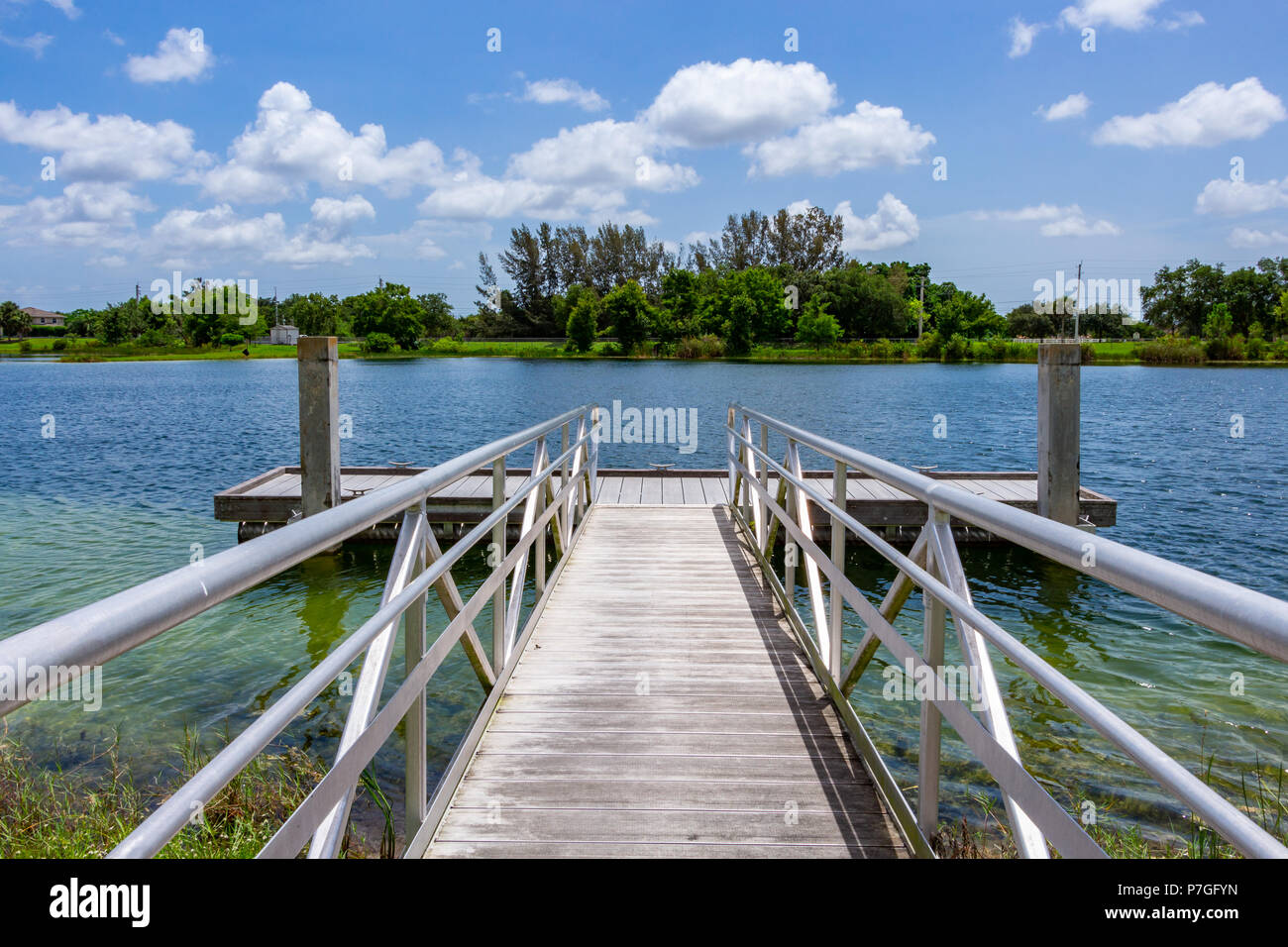 Ramp to boat dock or fishing platform on blue green lake with trees ...
