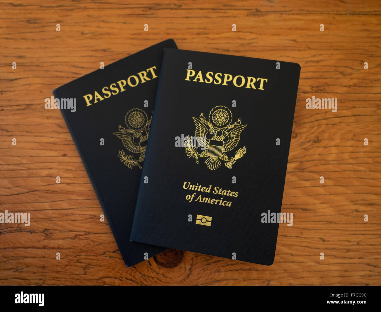 Two navy blue US Passports on a wooden table top and photographed from ...
