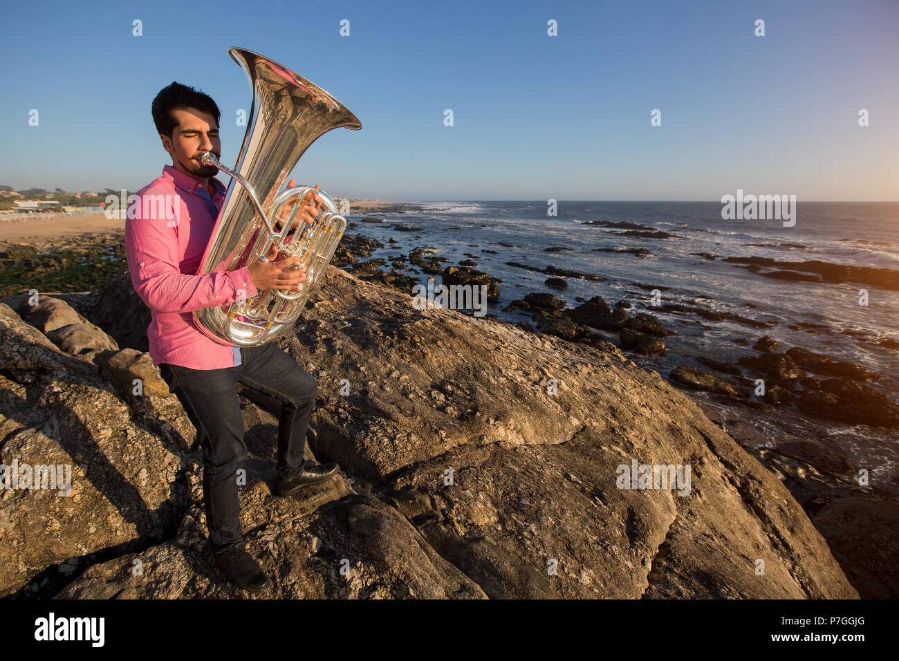 Musician play to Tuba musical instrument on romantic rocky sea shore ...