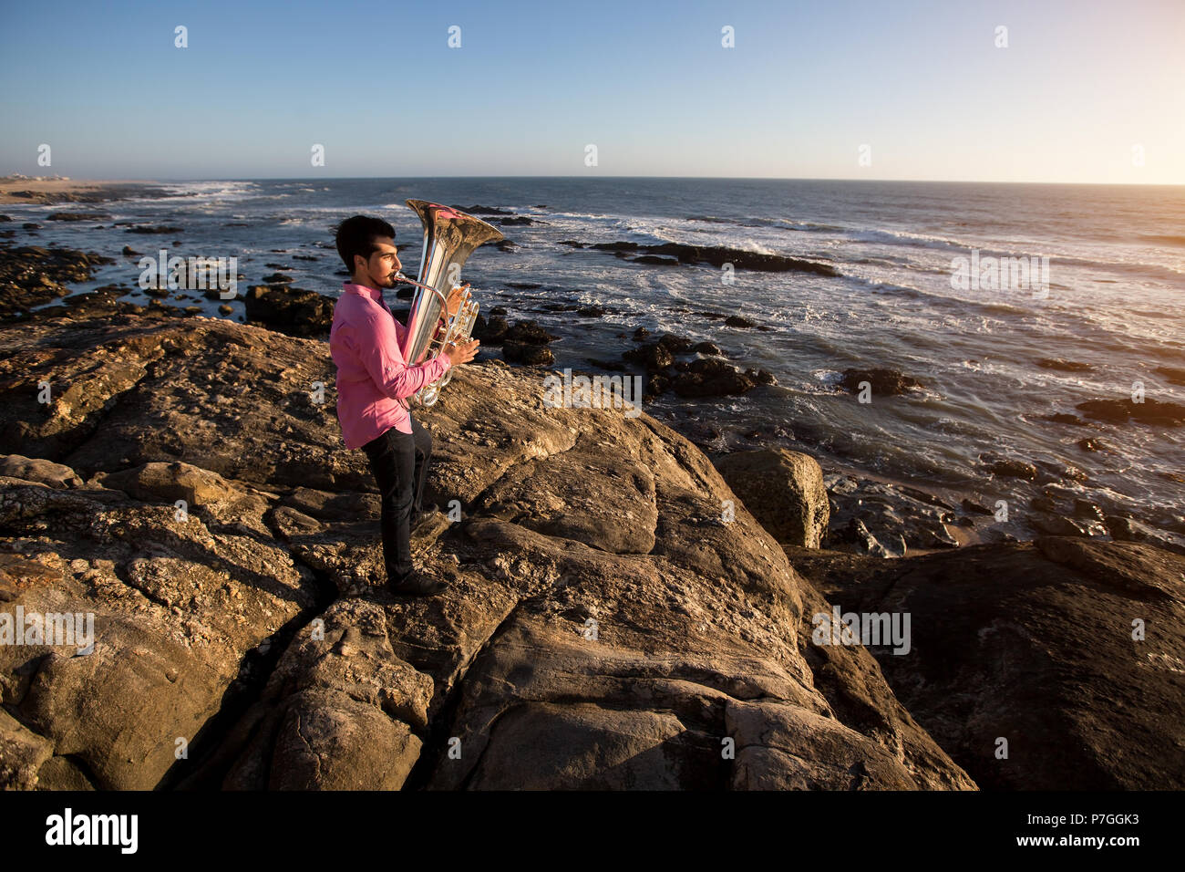 Musician play to Tuba musical instrument on romantic rocky sea shore ...