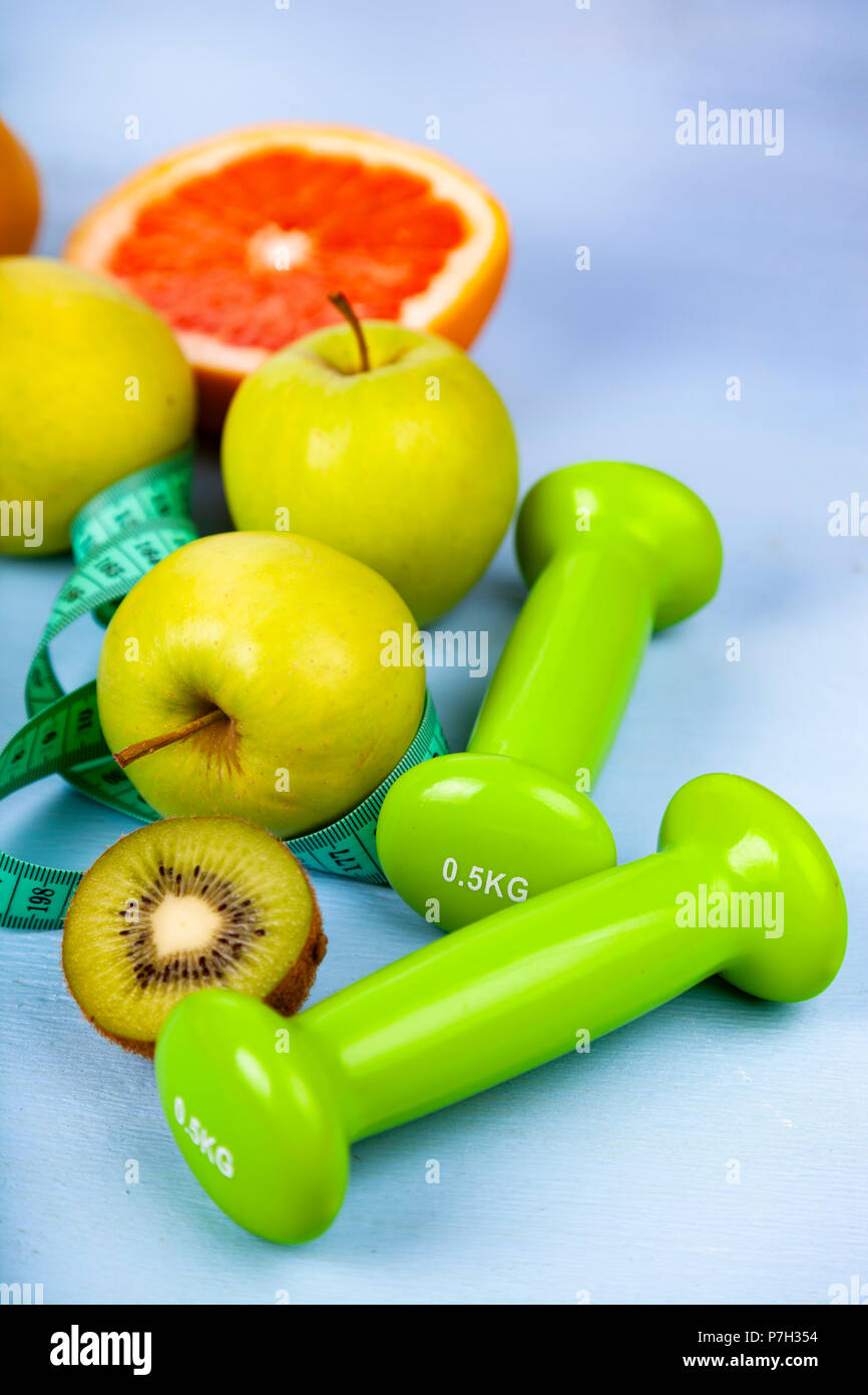Food for diet and dumbbells on a wooden background. Concept of diet and ...