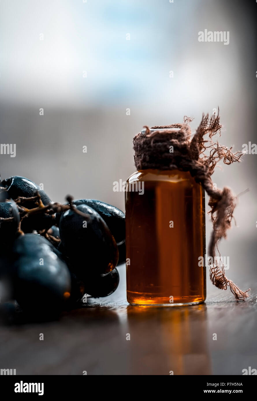 Close up of Black grapes oil on a wooden surface in dark Gothic colors ...