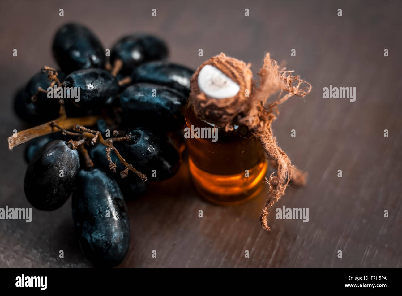 Close up of Black grapes oil on a wooden surface in dark Gothic colors ...