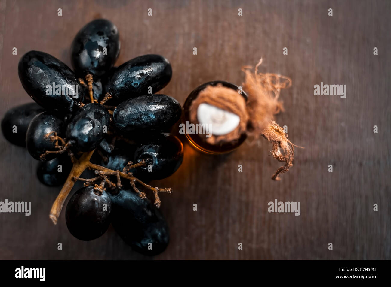 Close up of Black grapes oil on a wooden surface in dark Gothic colors ...