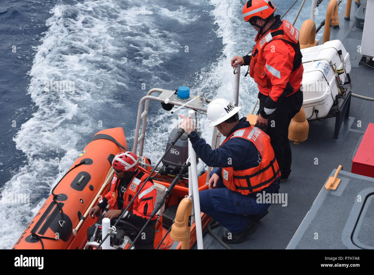 Crewmembers from the Coast Guard Cutter Orcas climb aboard a small boat ...