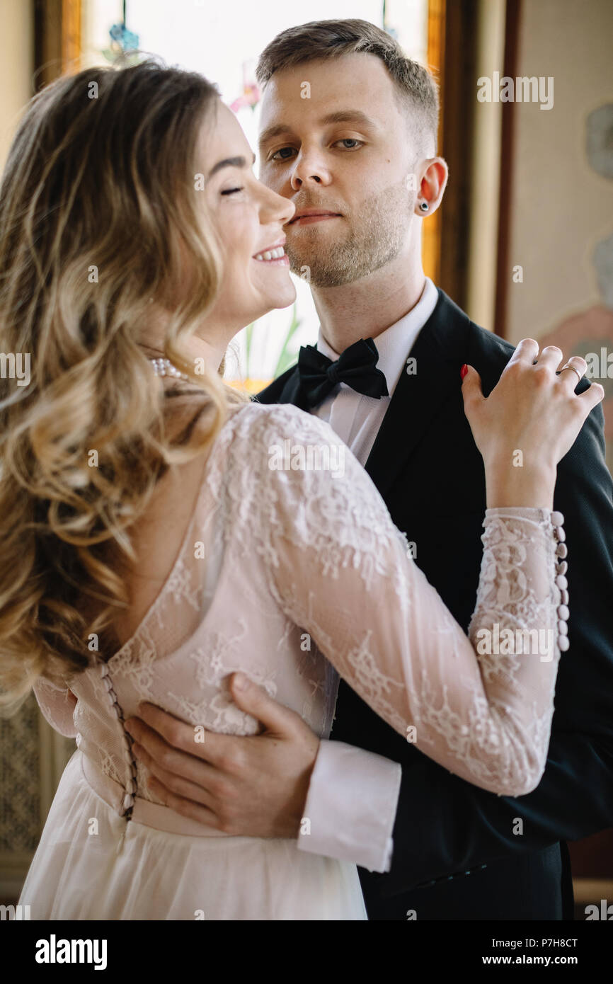 Wedding couple indoors is hugging each other. Beautiful bride in white ...