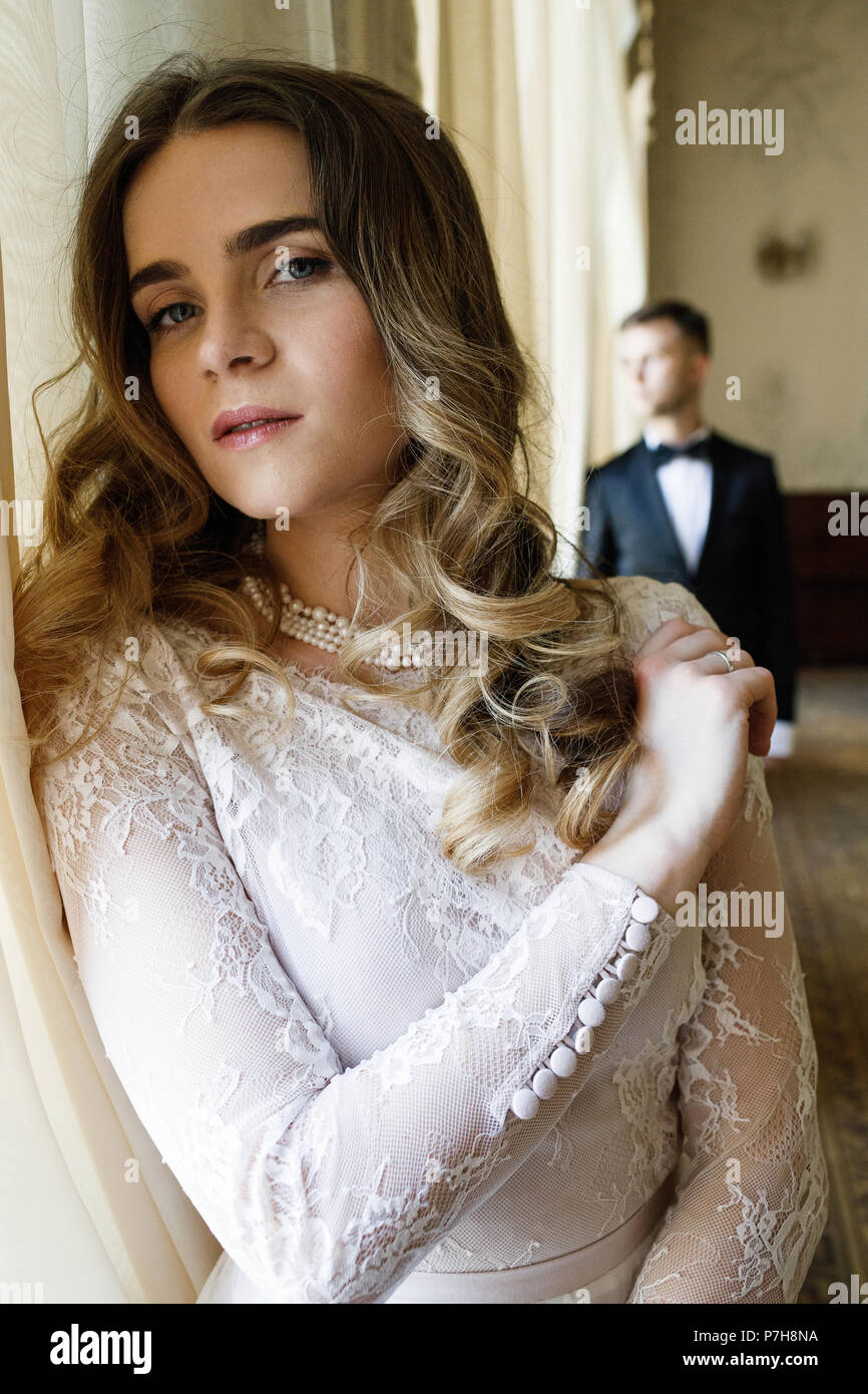 Wedding couple indoors is hugging each other. Beautiful bride in white ...