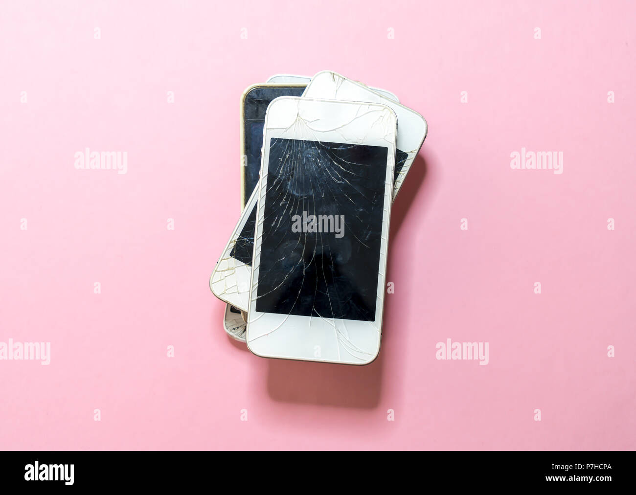 pile of old broken mobile phones with pink background Stock Photo - Alamy