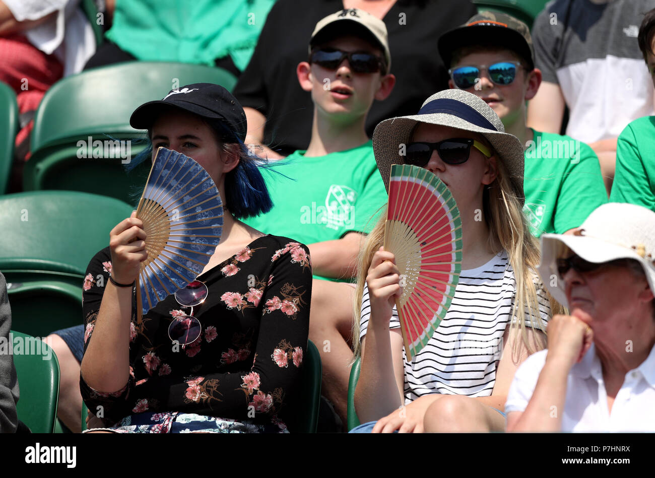 Spectators use a fan to keep themselves cool in the heat on day five of ...