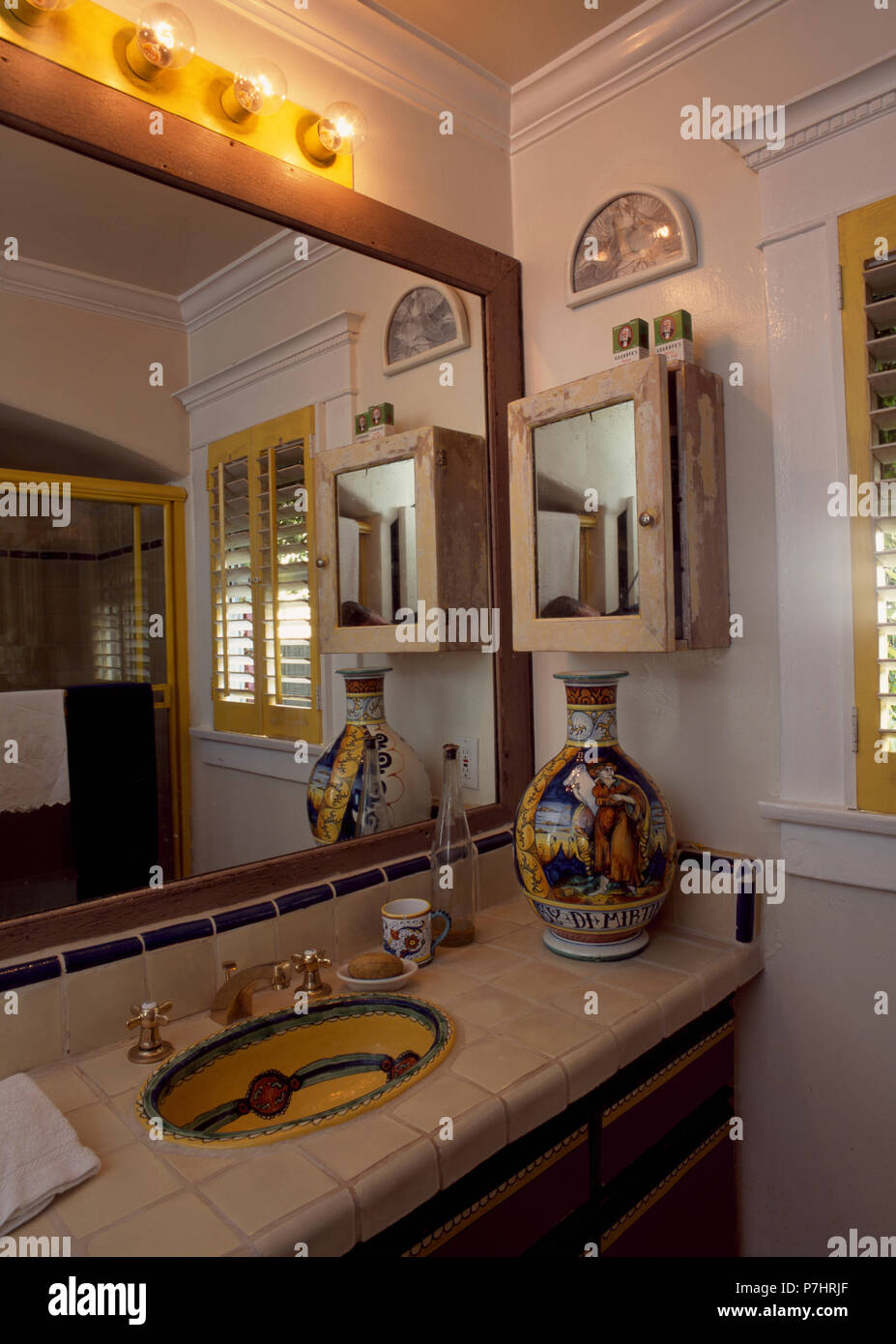 Row of lights above rectangular mirror and pottery basin set into tiled ...