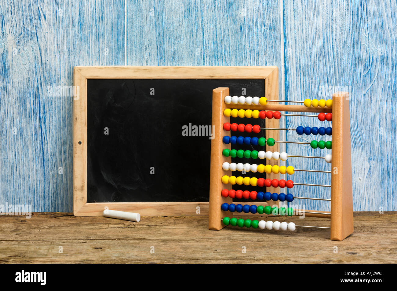 Blank vintage chalkboard and toy abacus on rustic table with blue wood ...