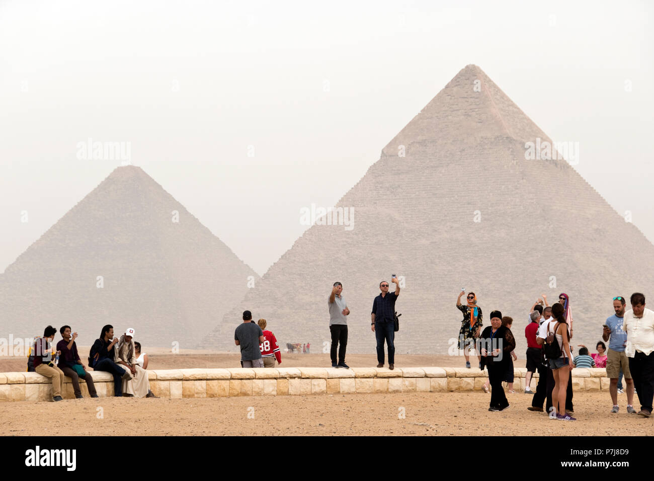 International tourists pose for photos at the Great Pyramid of Giza ...