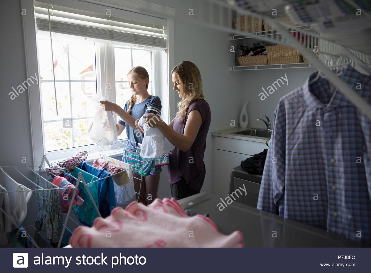 Mother and daughter doing laundry in laundry room Stock Photo - Alamy