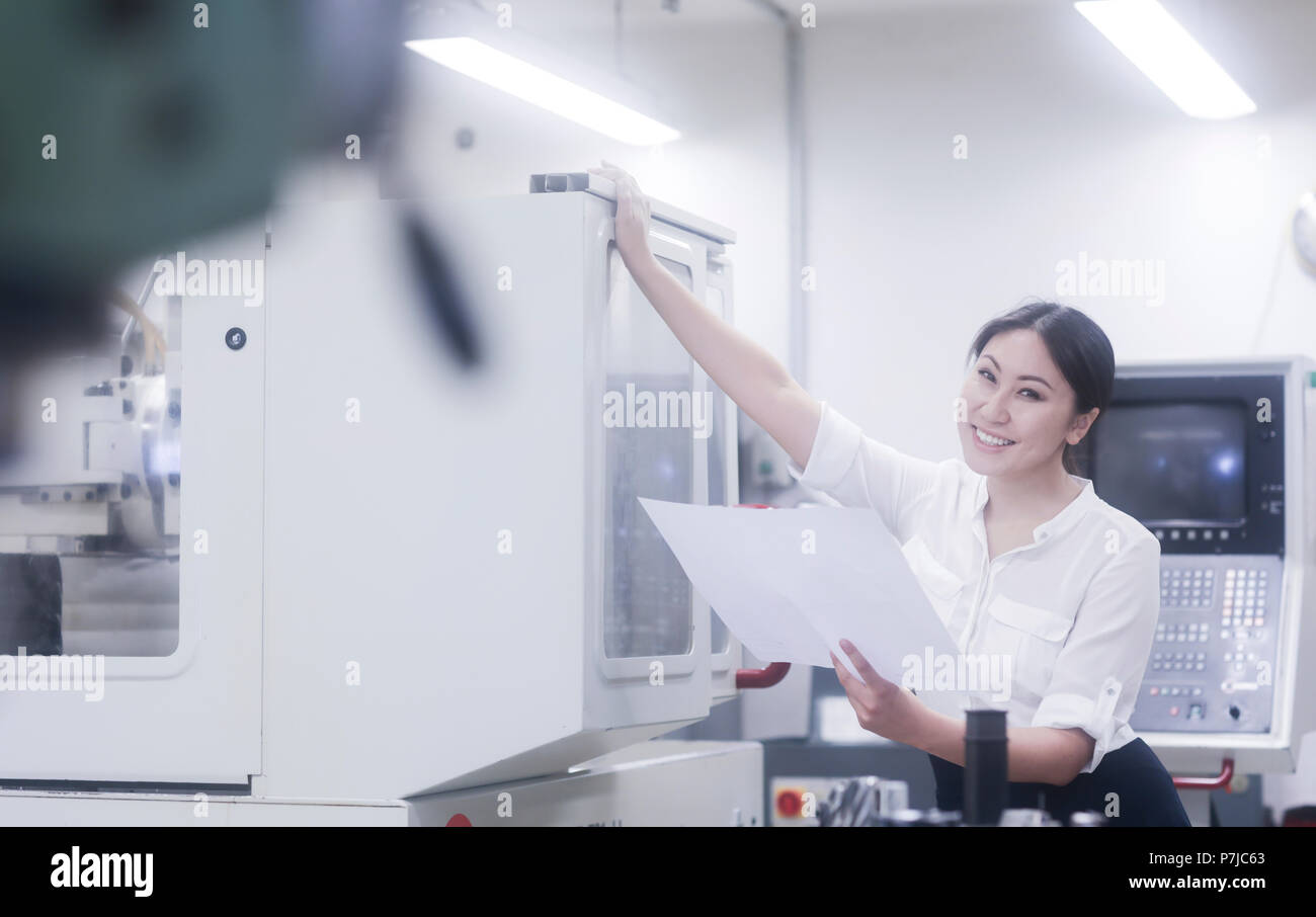 Smiling female engineer looking at a technical drawing Stock Photo - Alamy