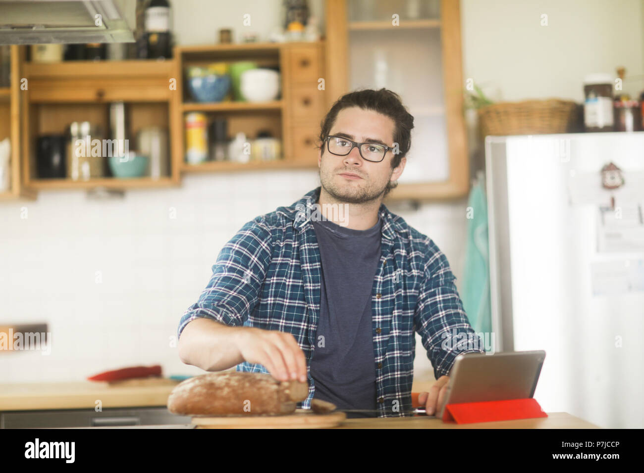 Man standing in kitchen slicing a loaf of bread Stock Photo - Alamy