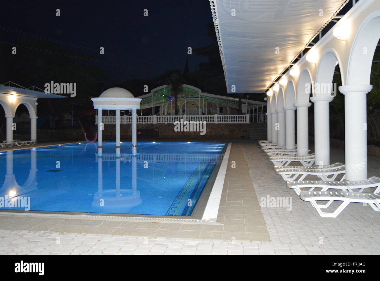 Night view of the luxurious pool with columns and arches, reflected in ...